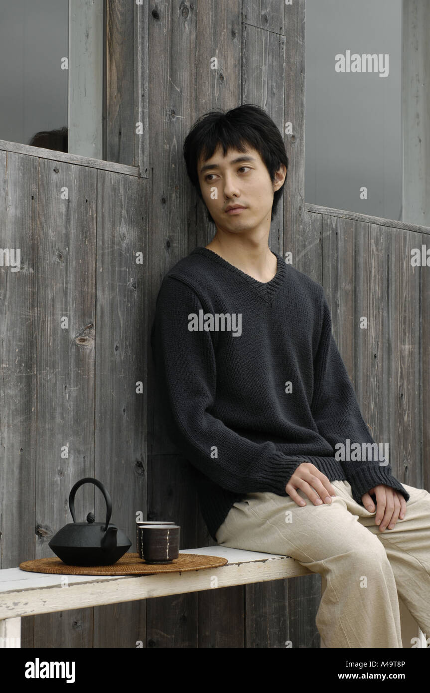 Side profile of a young man sitting on a bench Stock Photo - Alamy