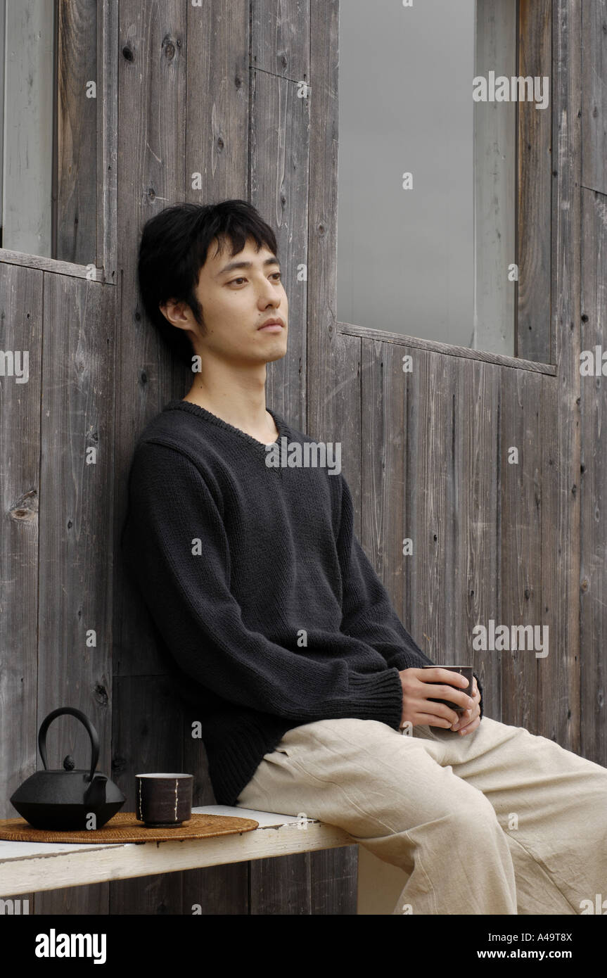 Side profile of a young man sitting on a bench Stock Photo - Alamy