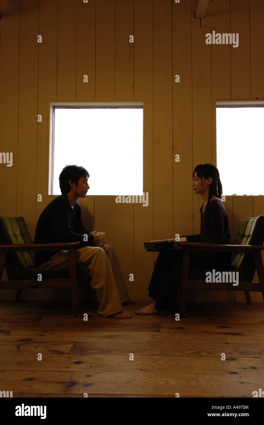 Side profile of a young couple sitting near windows Stock Photo - Alamy