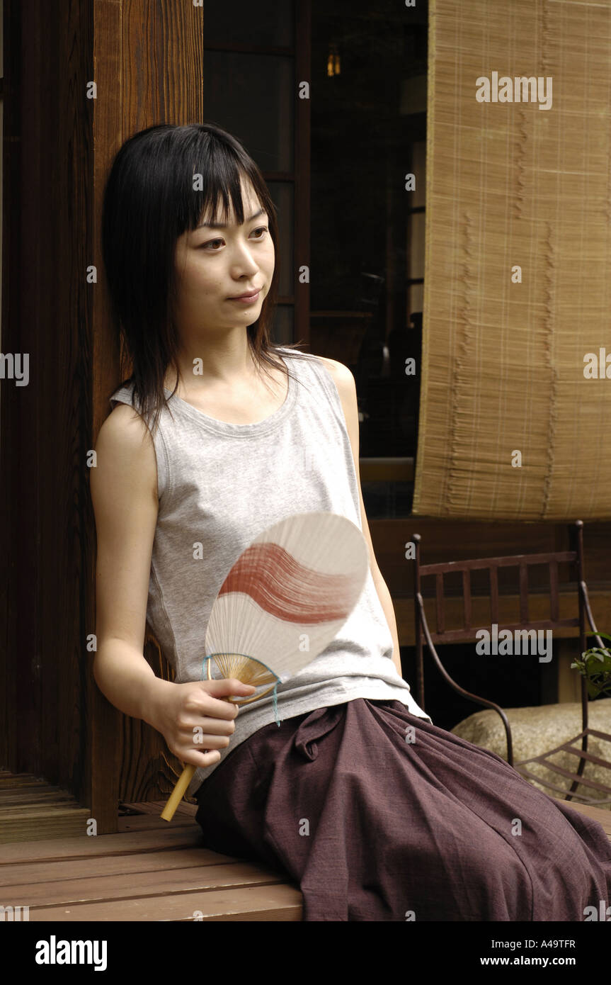 Young woman sitting and holding a folding fan Stock Photo - Alamy