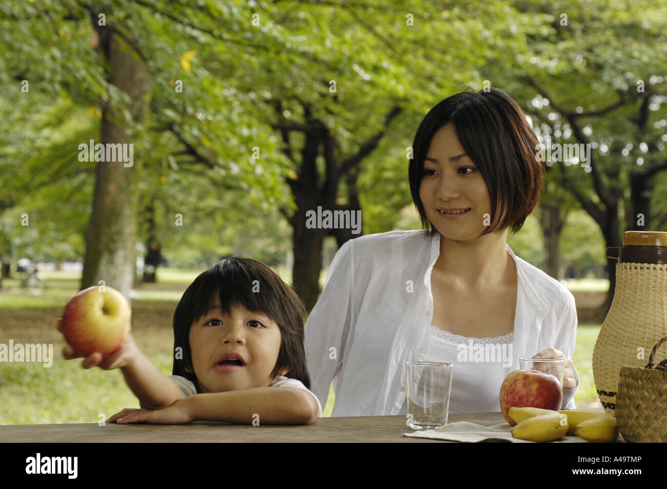 Girl holding an apple beside her mother Stock Photo - Alamy