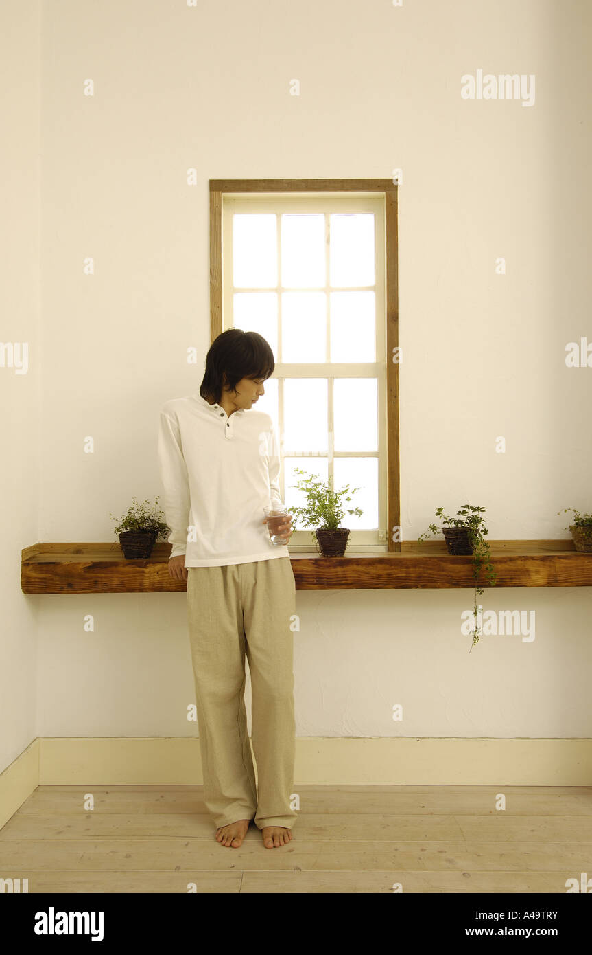 Young man standing in front of a window with a glass Stock Photo - Alamy