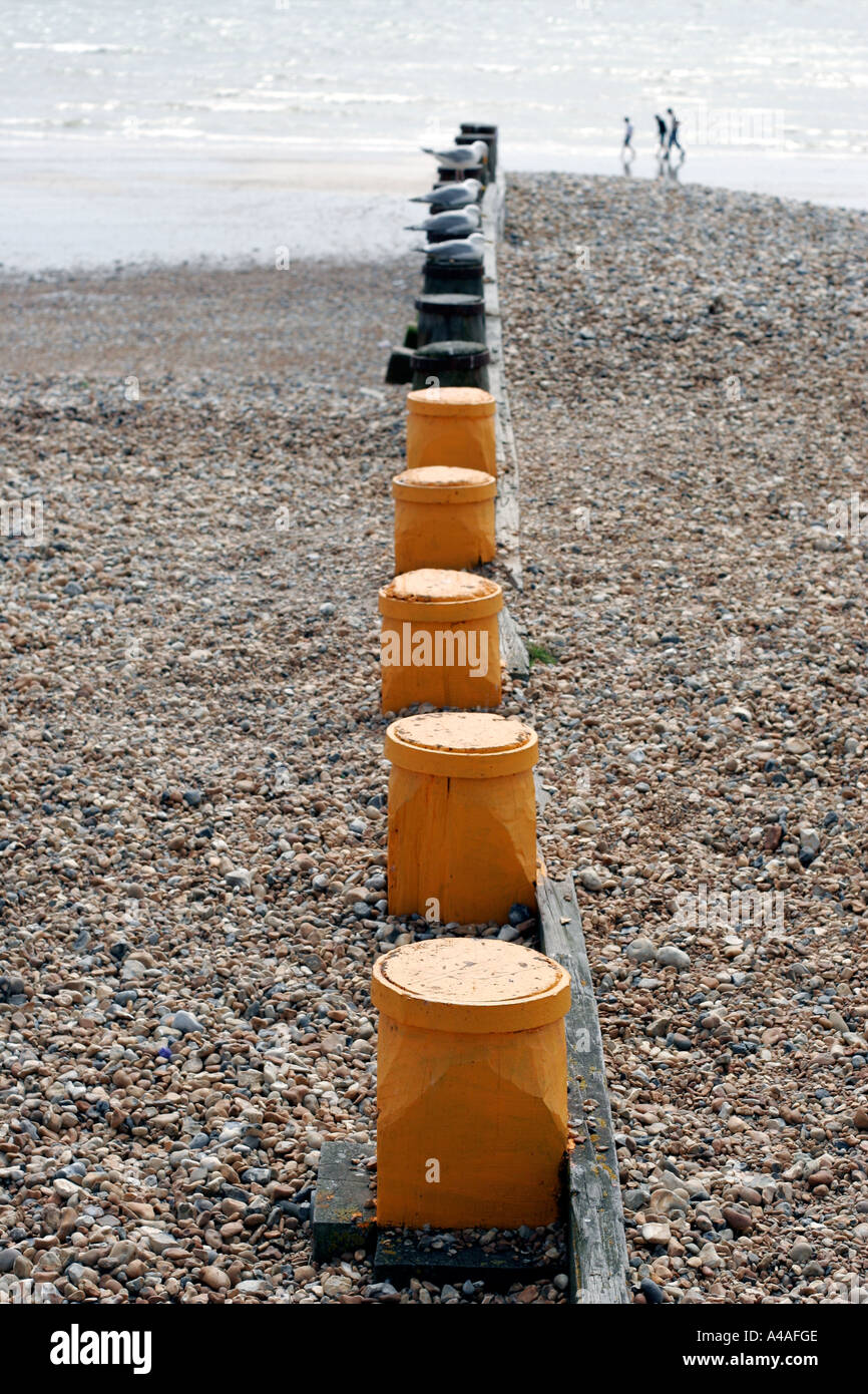 Yellow painted wooden bollards on Eastbourne beach Stock Photo - Alamy