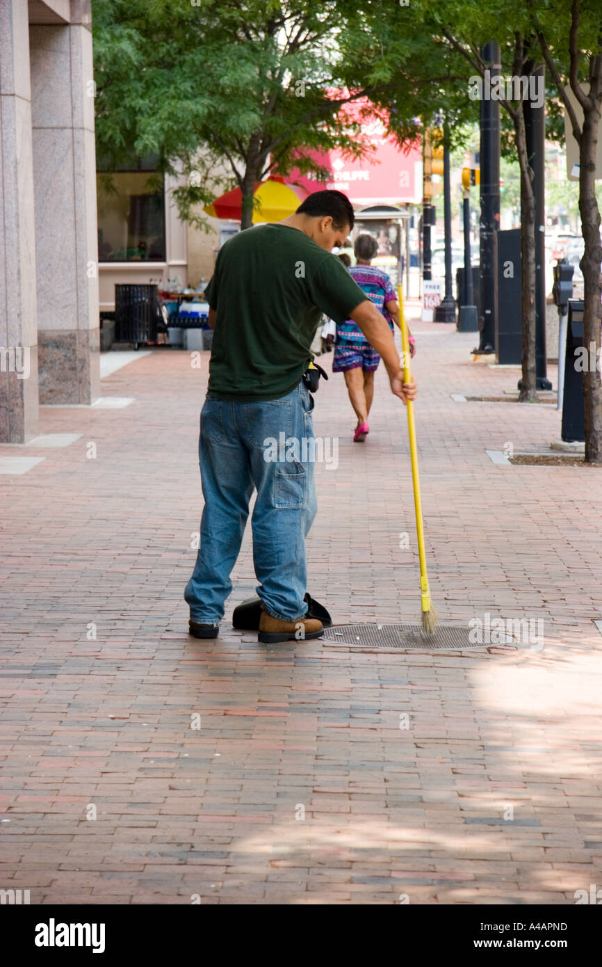 Man sweeping the sidewalk in front of a shop Stock Photo - Alamy