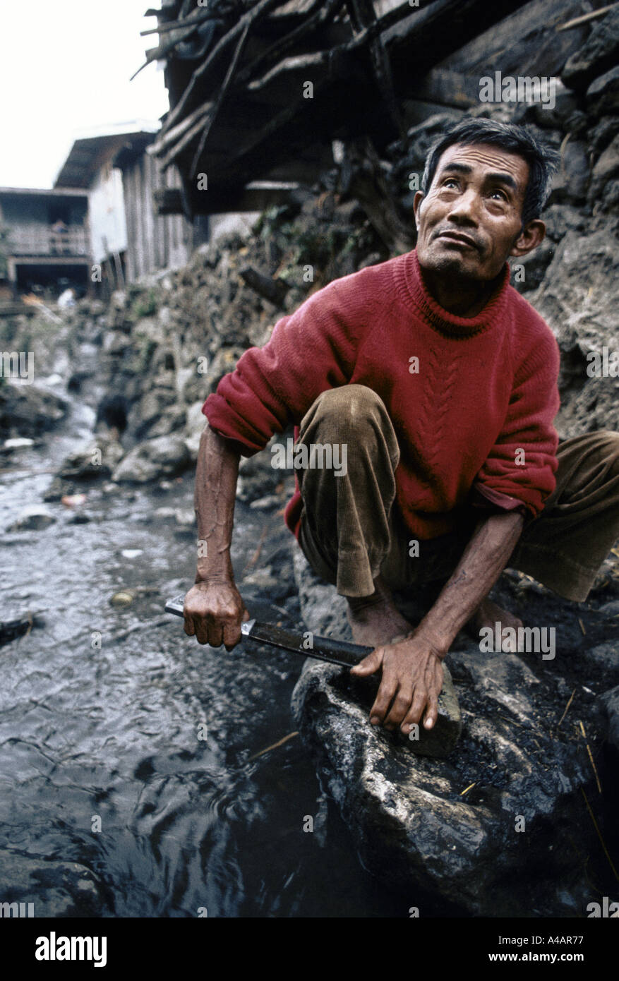 Philippines villager sharpens his machete using hot spring water in the ...
