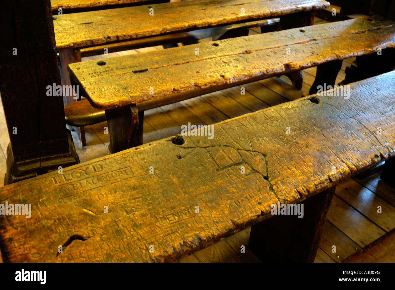 Tables and benches with graffiti in an old class room at Eaton College ...