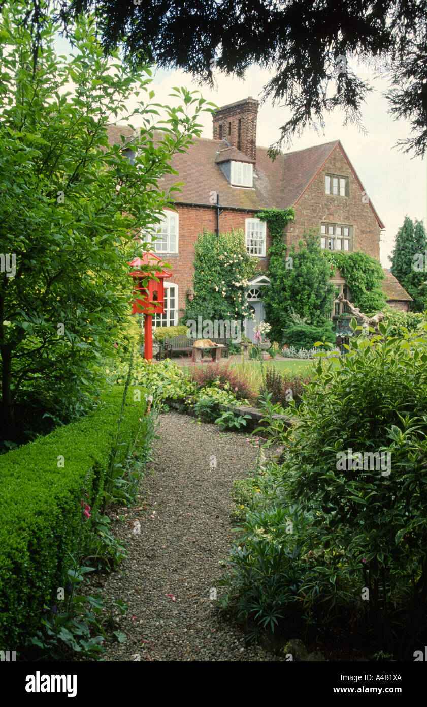 pathway through garden under Yew tree to large house Stock Photo - Alamy
