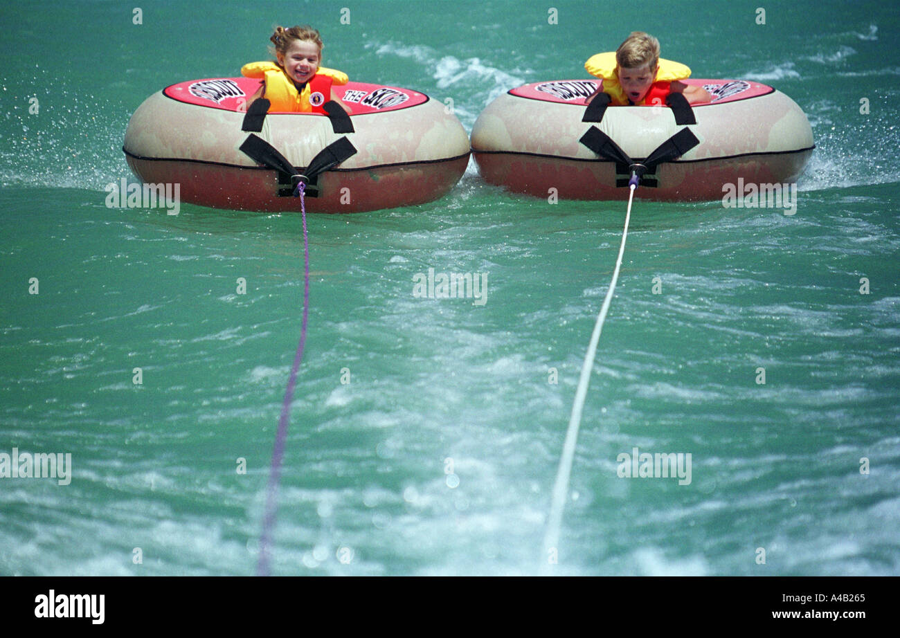 Two children enjoying a ride in a tube Stock Photo - Alamy