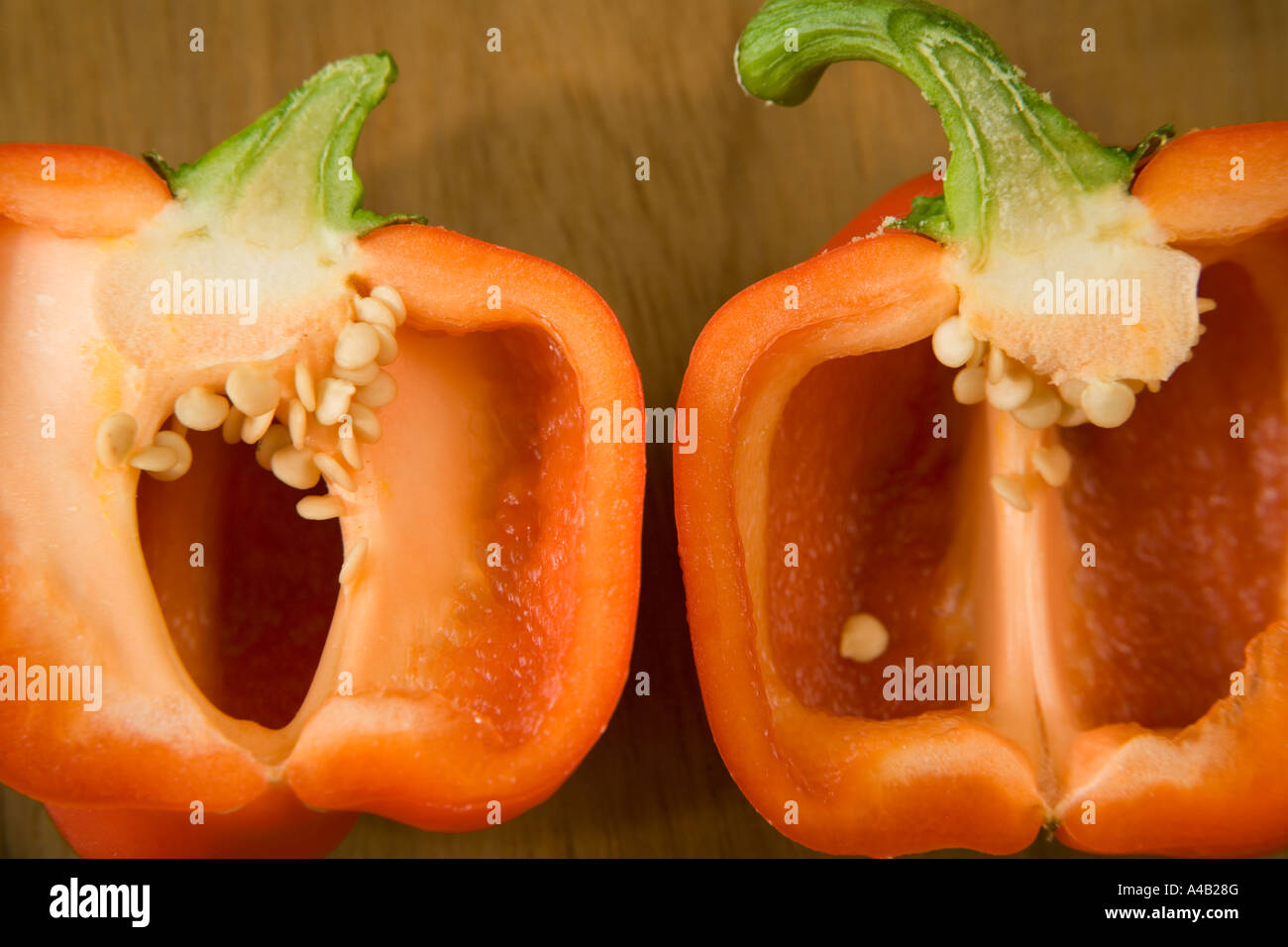 Two red pepper halves showing the inside with seeds placed on a wooden ...