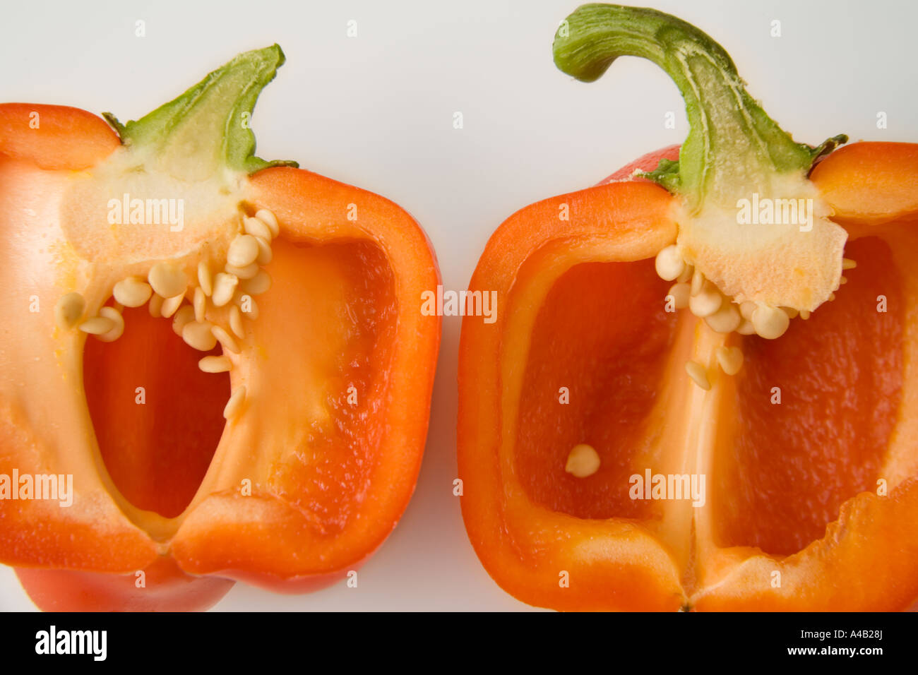 Two red pepper halves showing the inside with seeds on a white ...