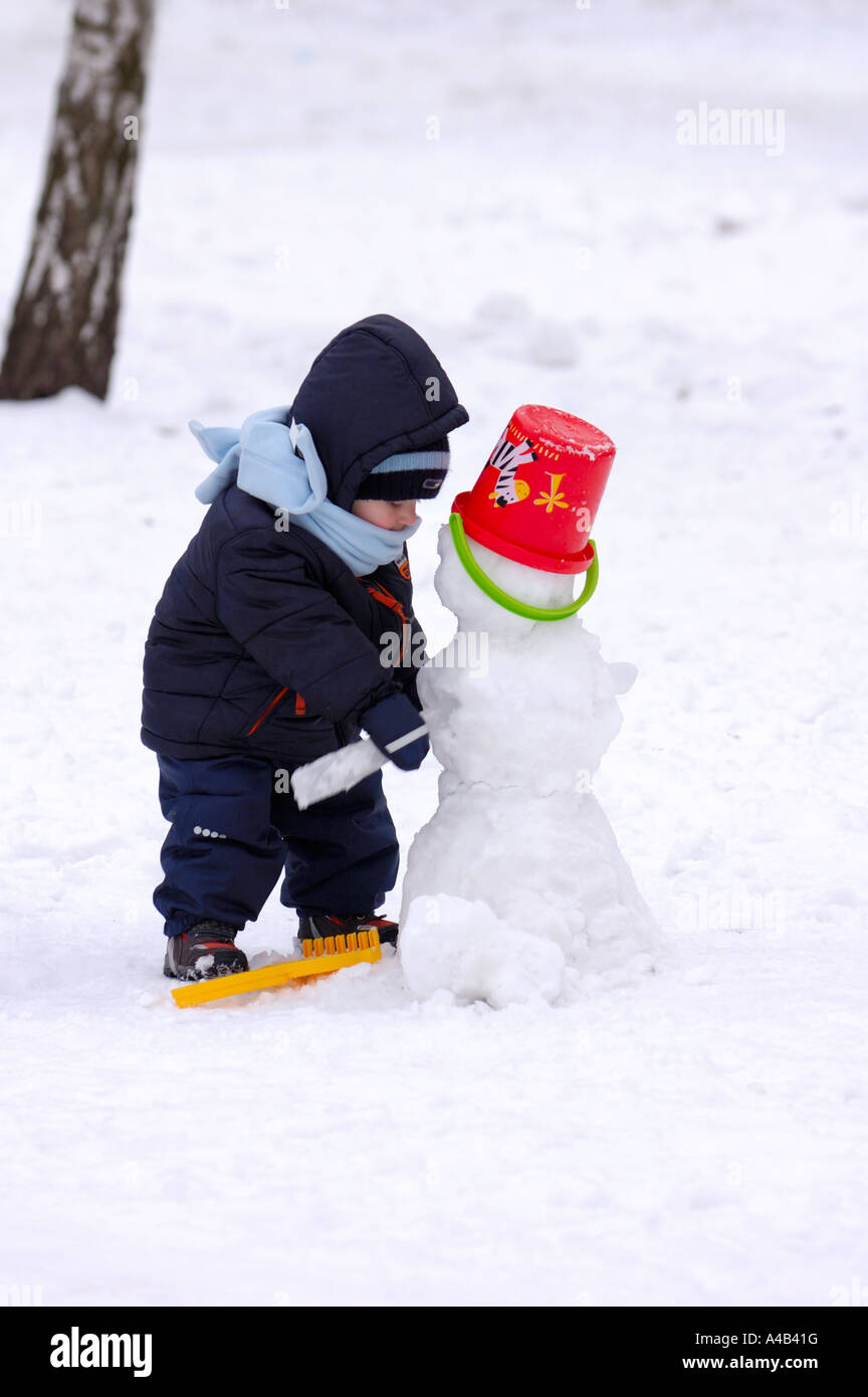Little boy making a snowman in winter Stock Photo - Alamy