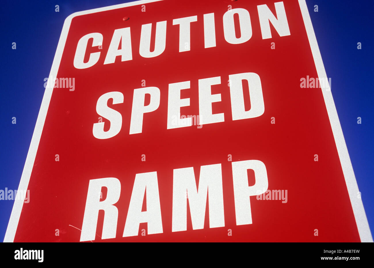 Close up at bold angle of red and white sign against deep blue sky ...