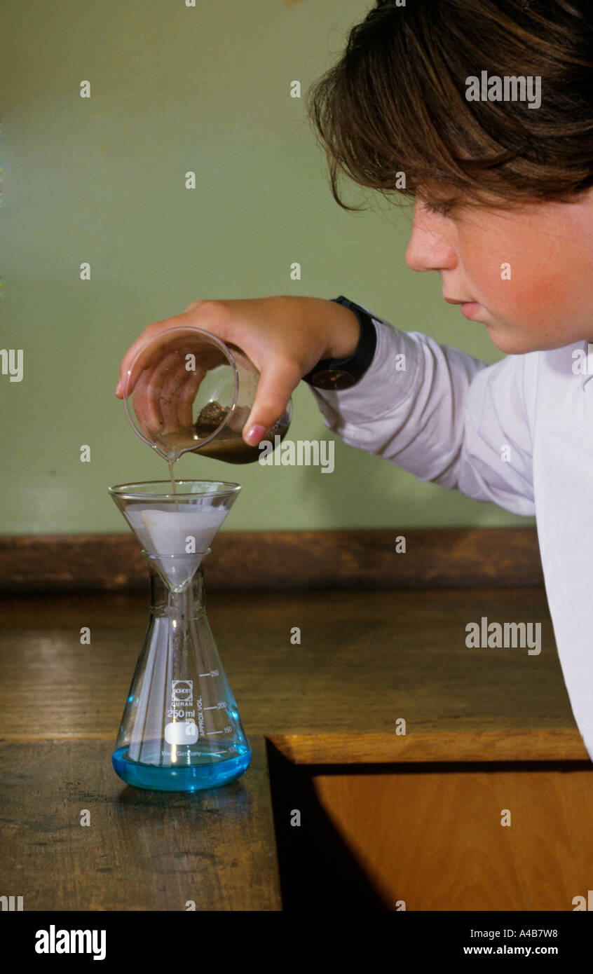 Boy in science class experiment filtering a liquid to remove impurities ...