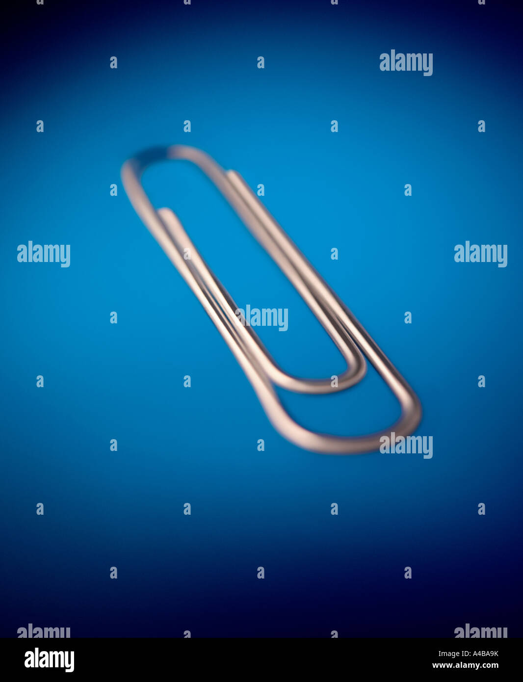 A paper clip on a blue background shot with split focus Stock Photo - Alamy