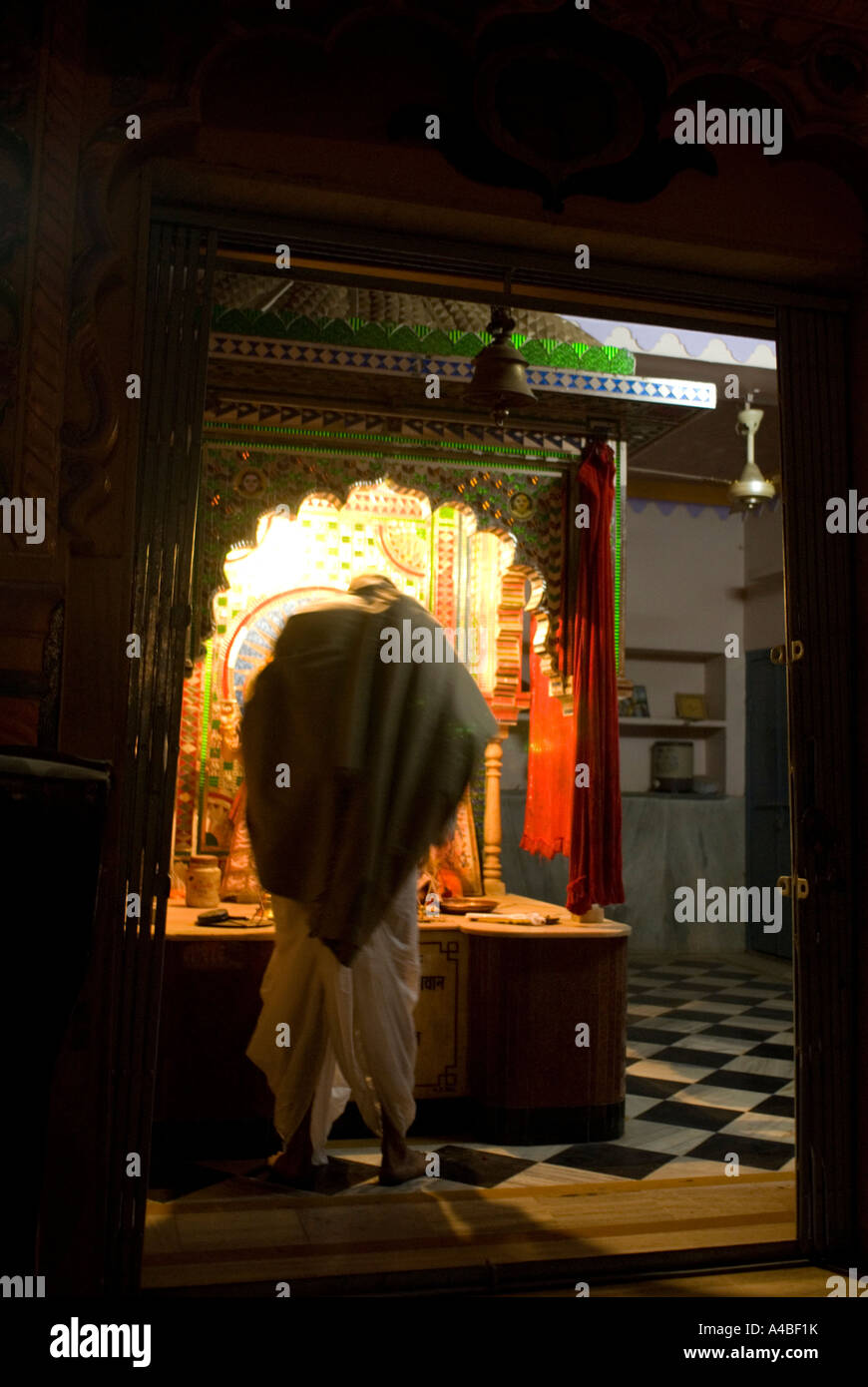 Stock image of Indian man in cloak performing a pooja at a Hindu shrine ...