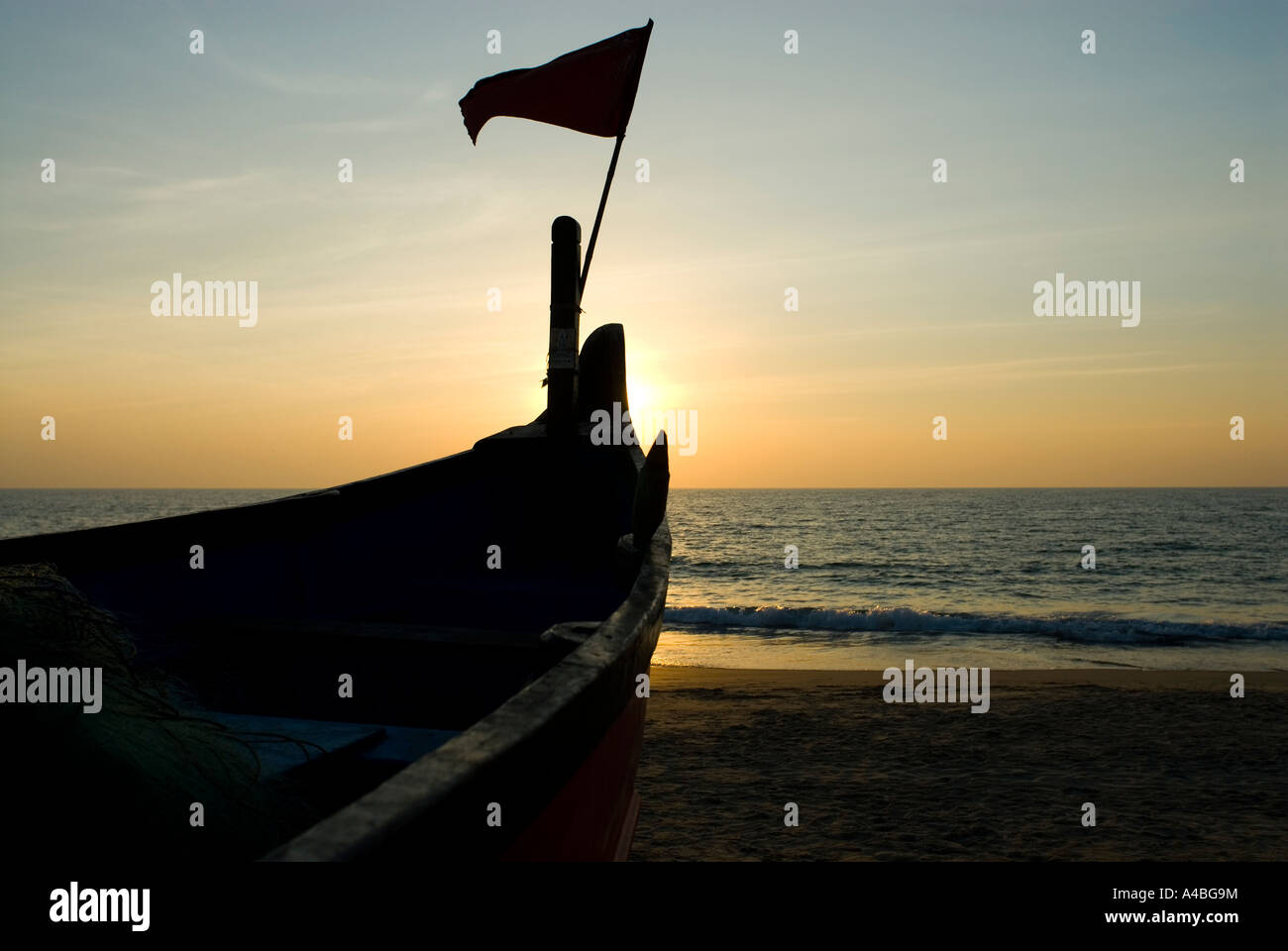 Stock image of an outrigger fishing boat in Goa with flag silhouetted ...