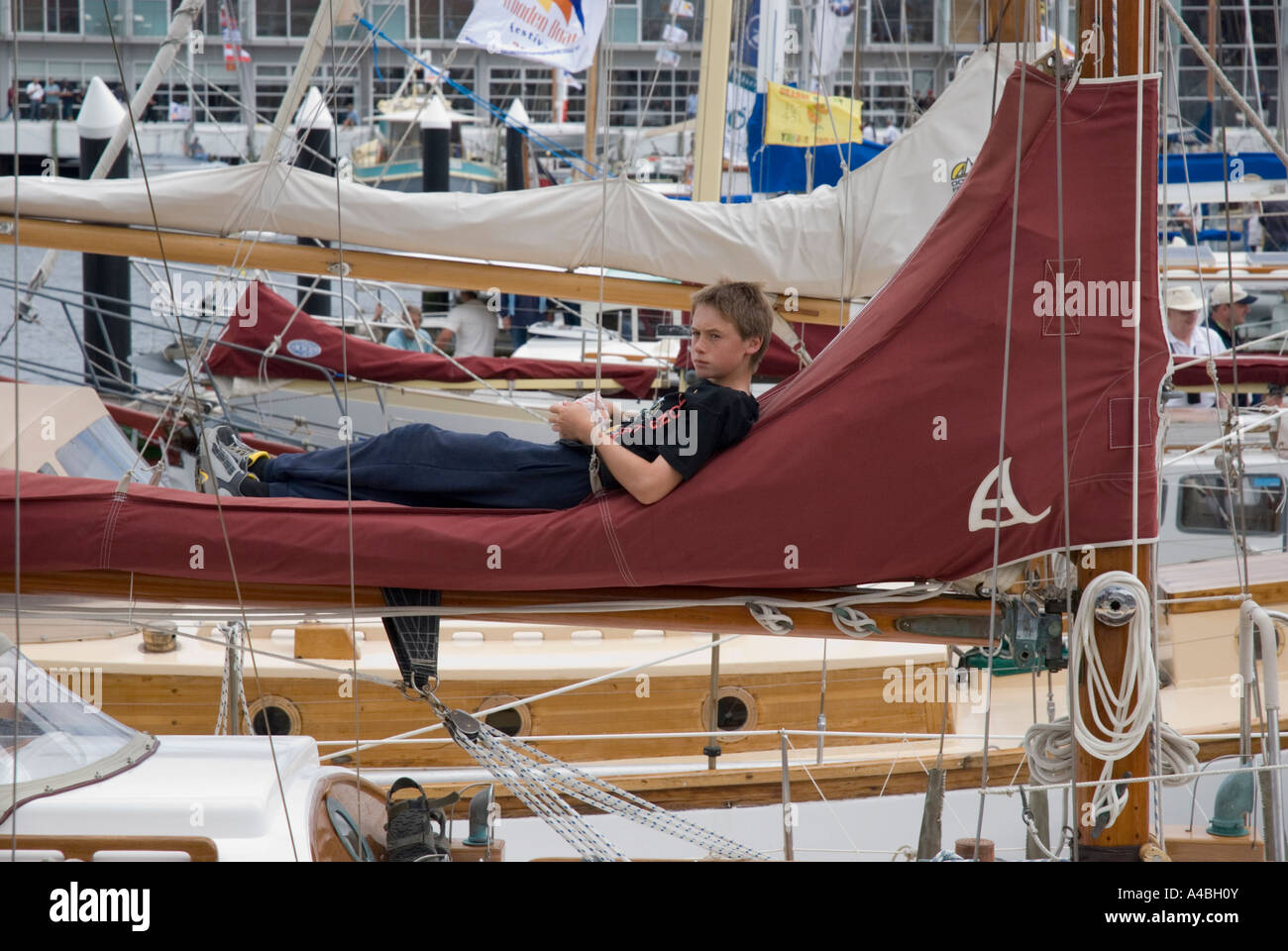A young lad relaxing on the boom of a yacht during the Australian ...