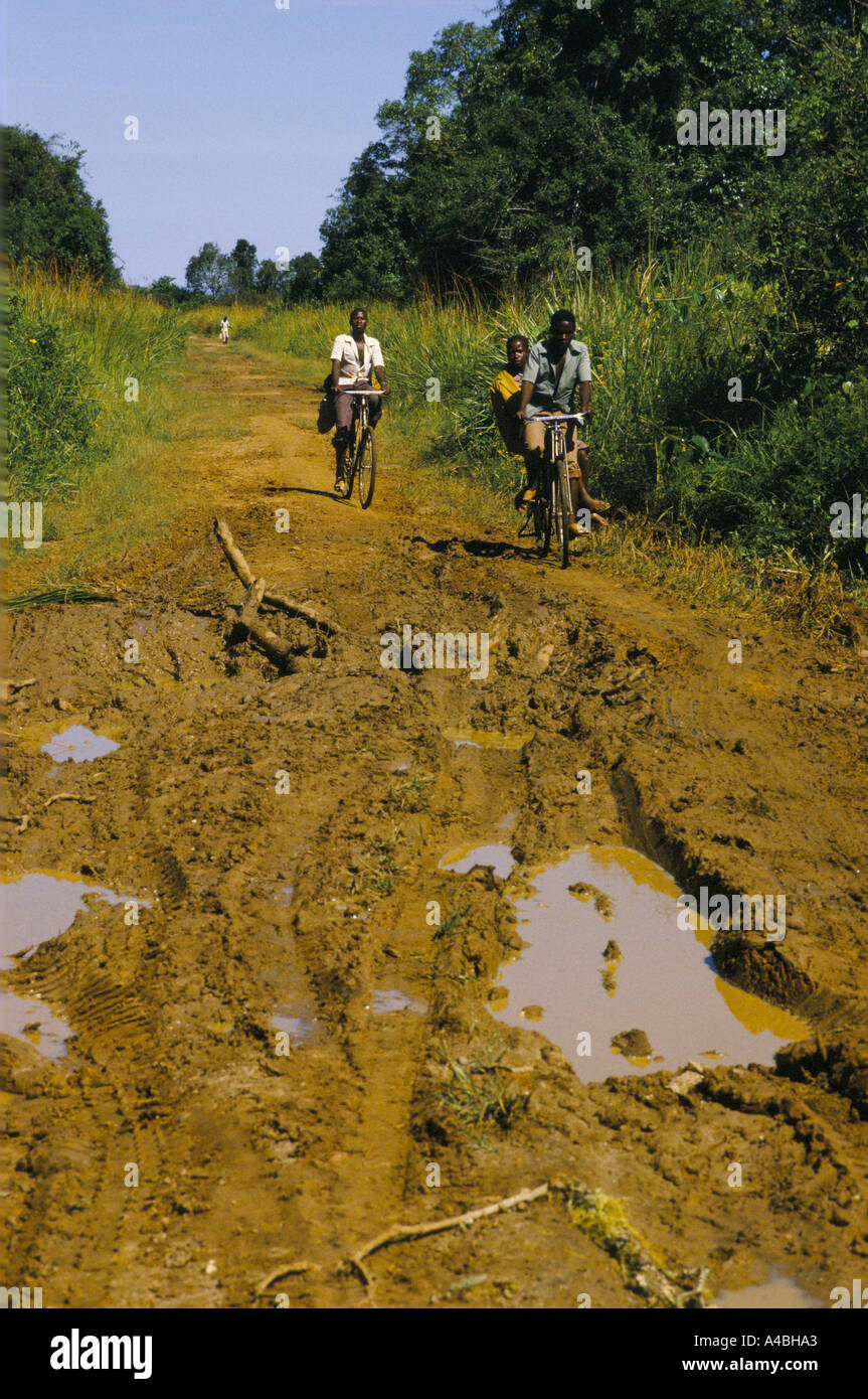 People cycle down a heavily rutted dirt road in Rakai province, rural ...