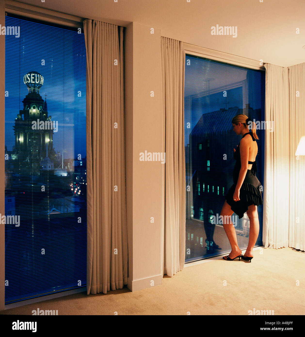 A beautiful girl looks out of the window of her apartment waiting for ...