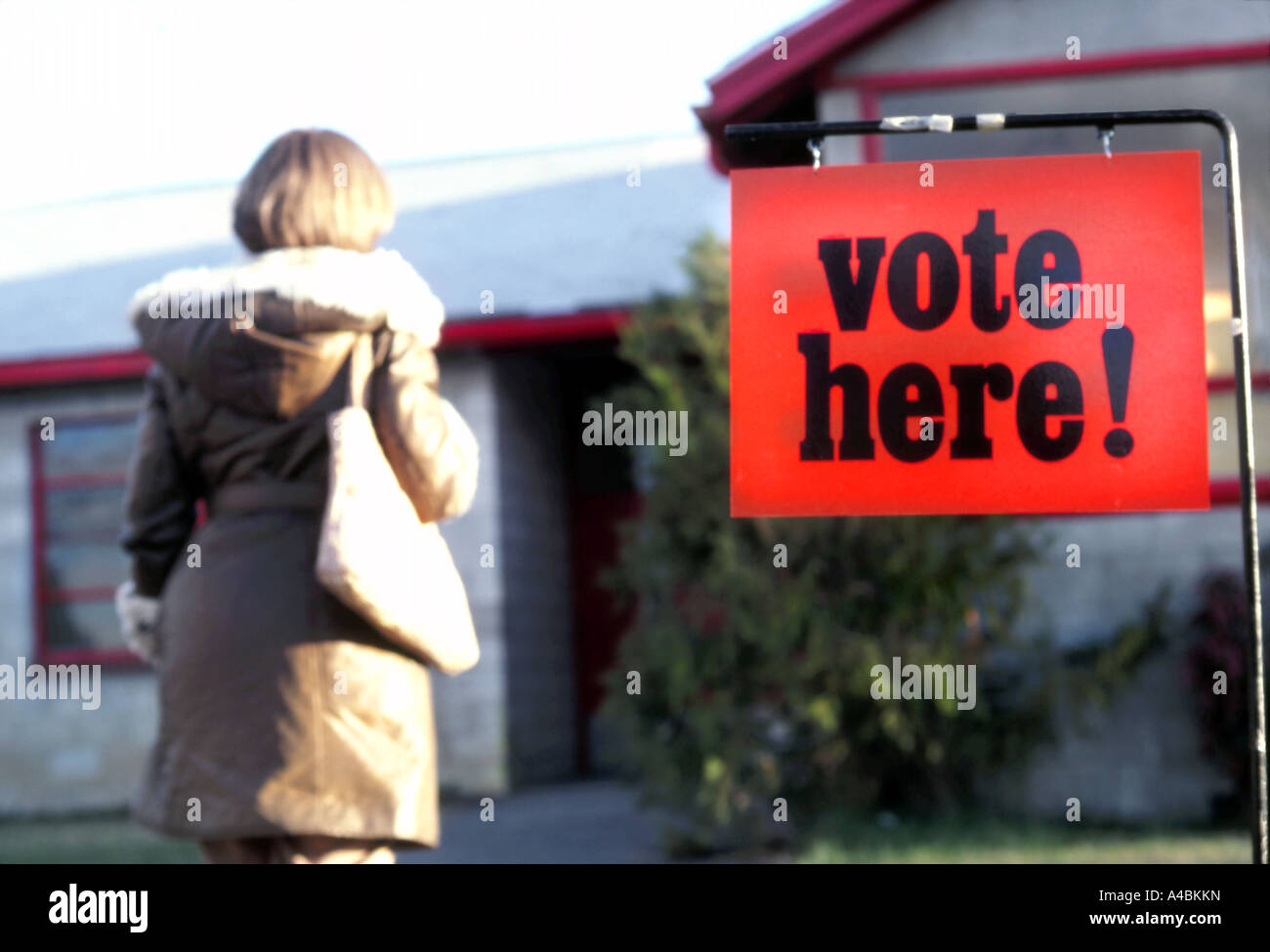Woman walking to voting place, beside "Vote Here" sign Stock Photo - Alamy