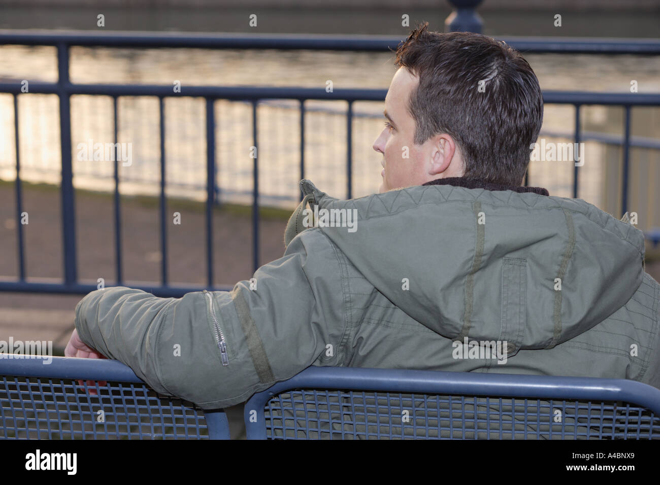 Young man sitting on a bench waiting Stock Photo - Alamy