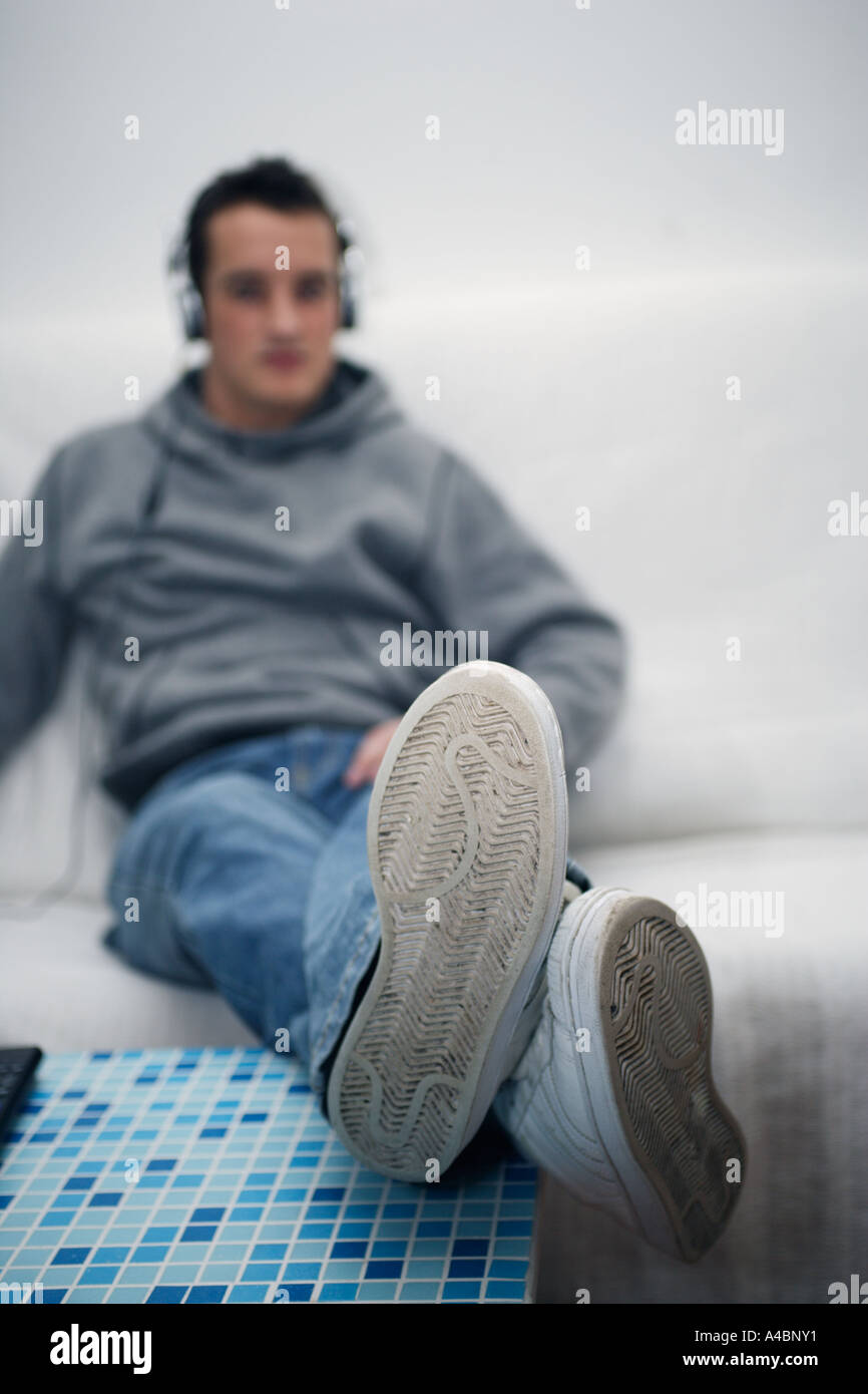 Young man sitting on a sofa relaxing with his feet on the table Stock ...
