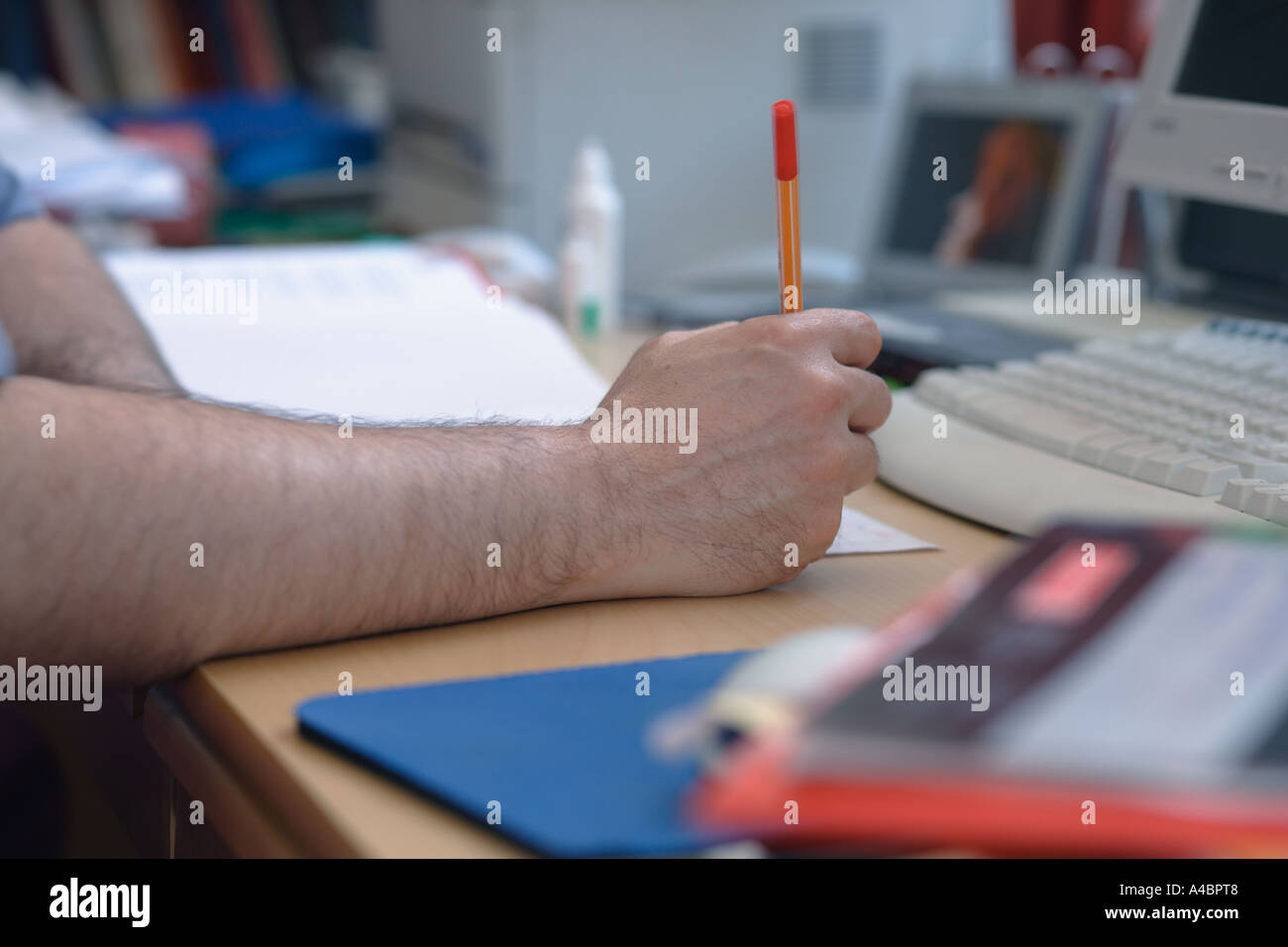 Man sitting at a desk writing Stock Photo - Alamy