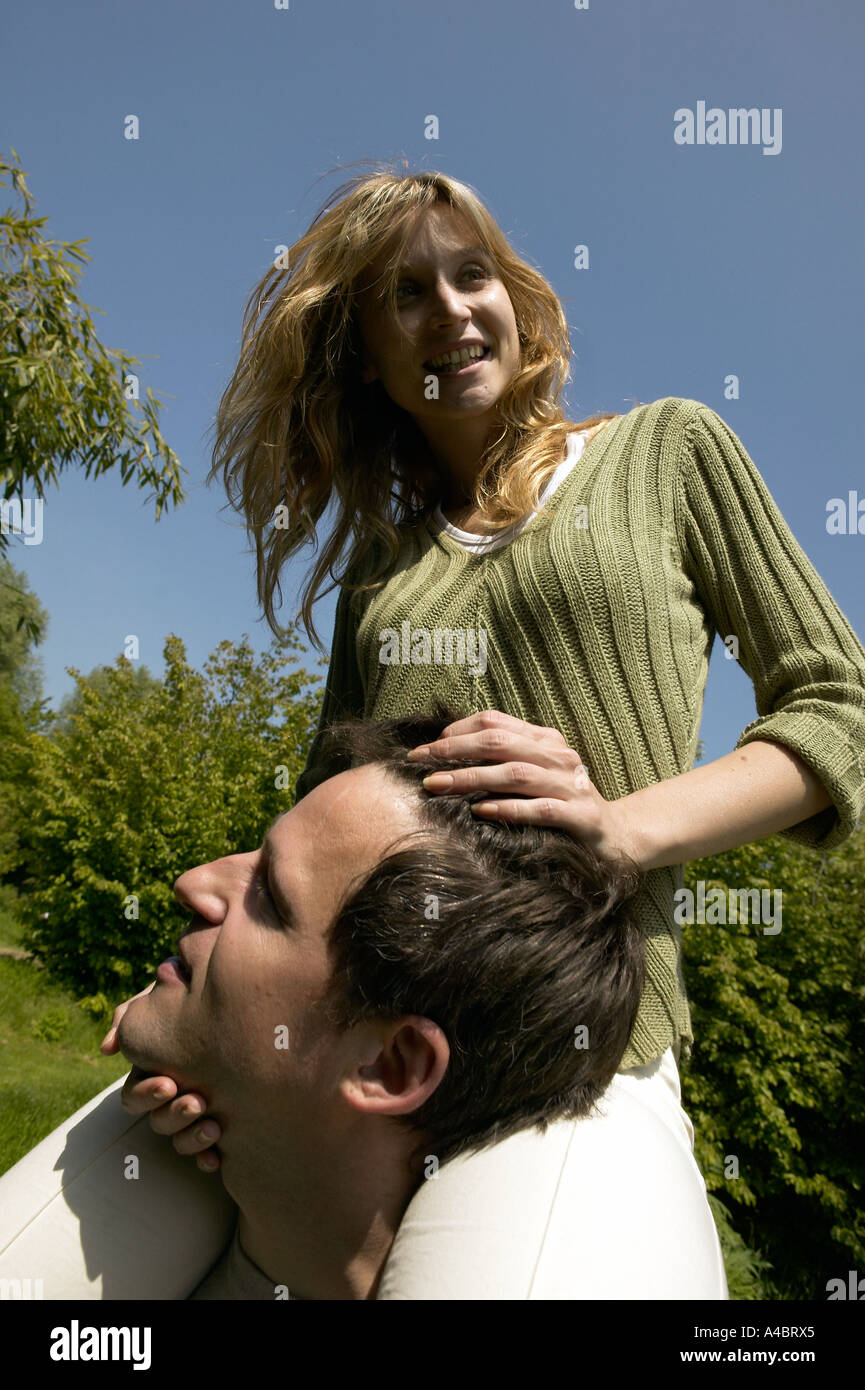Couple in park, woman sitting on man's shoulders Stock Photo - Alamy