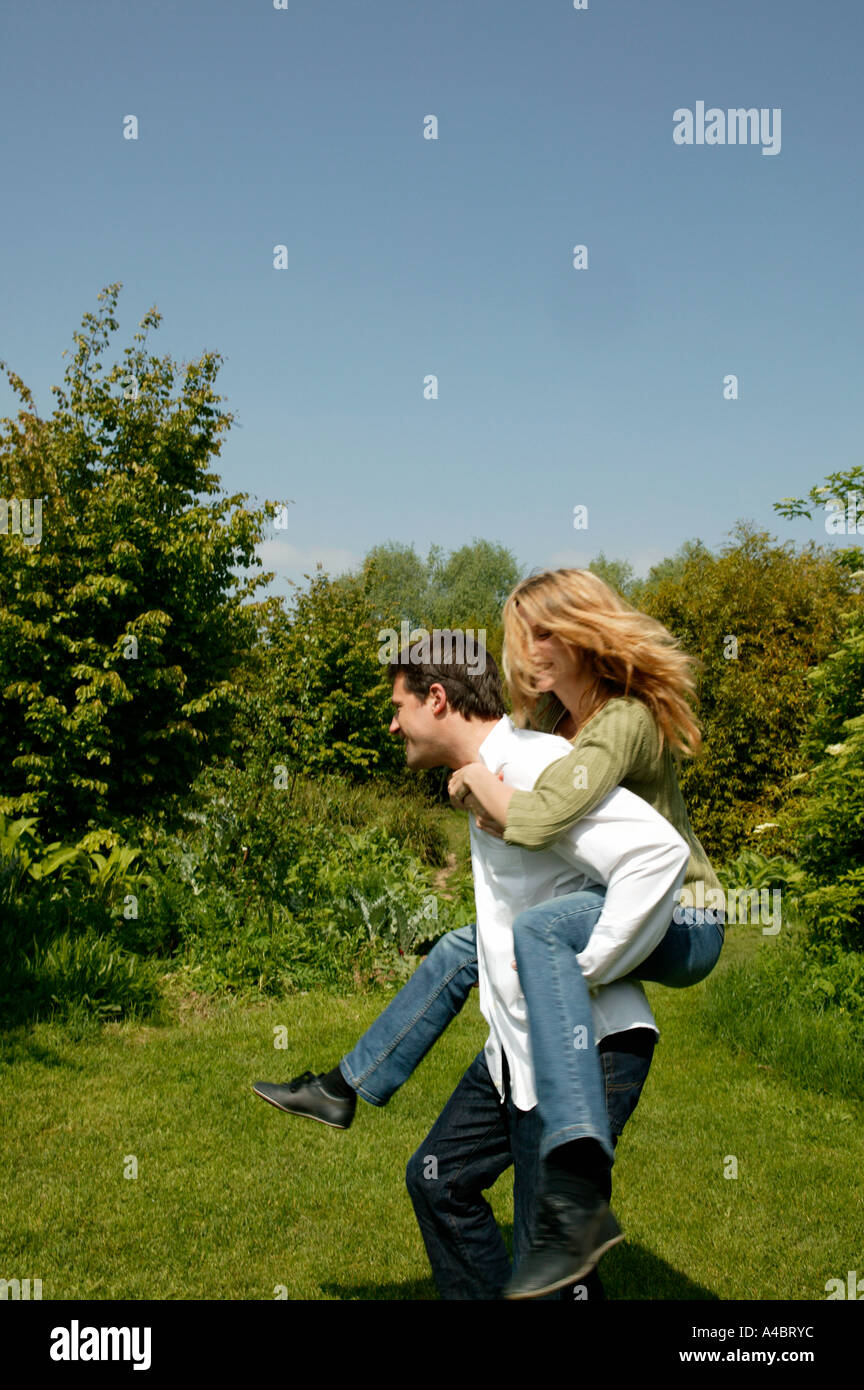 Young Couple Playing In Park Man Carrying Woman On His Back Stock