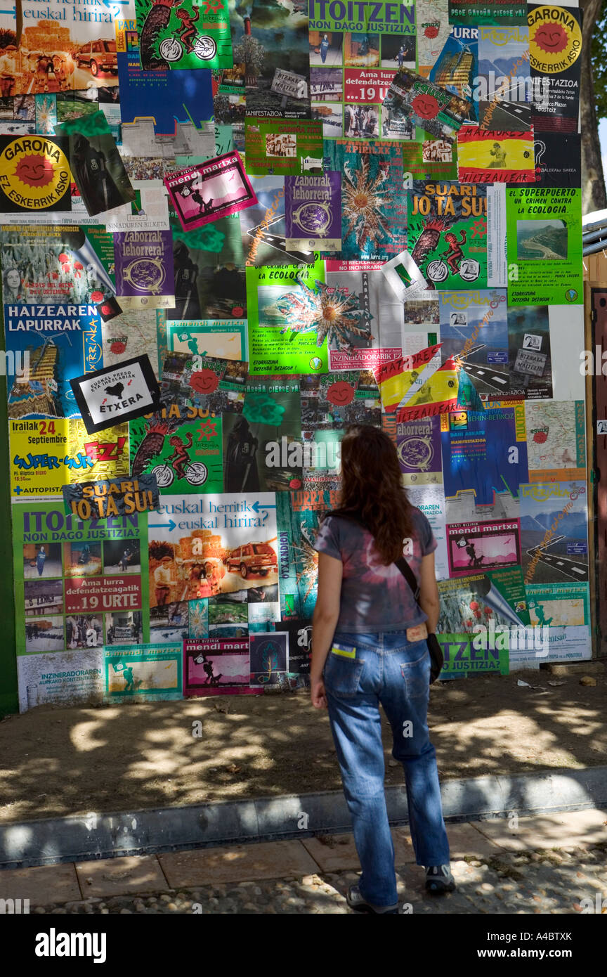 Woman standing and reading posters in Basque language Euskara stuck on ...