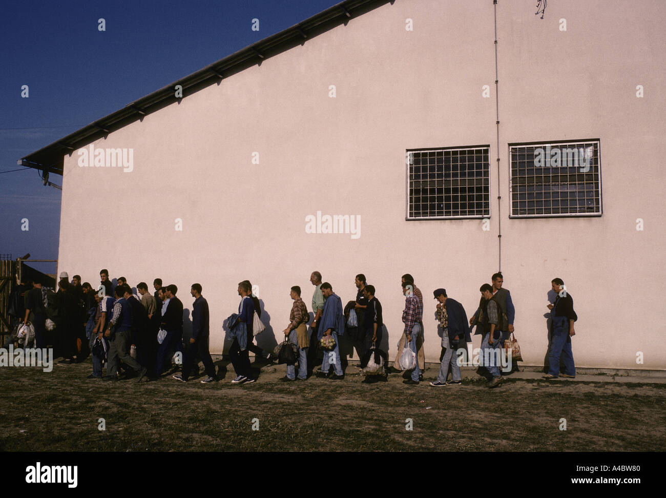 A line of men enter a building compound at Batkovici prison camp where ...