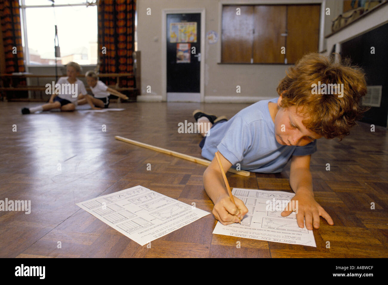 SCHOOL BOY MAKING NOTES ON EXERCISES DURING P.E. LESSON IN A PRIMARY ...