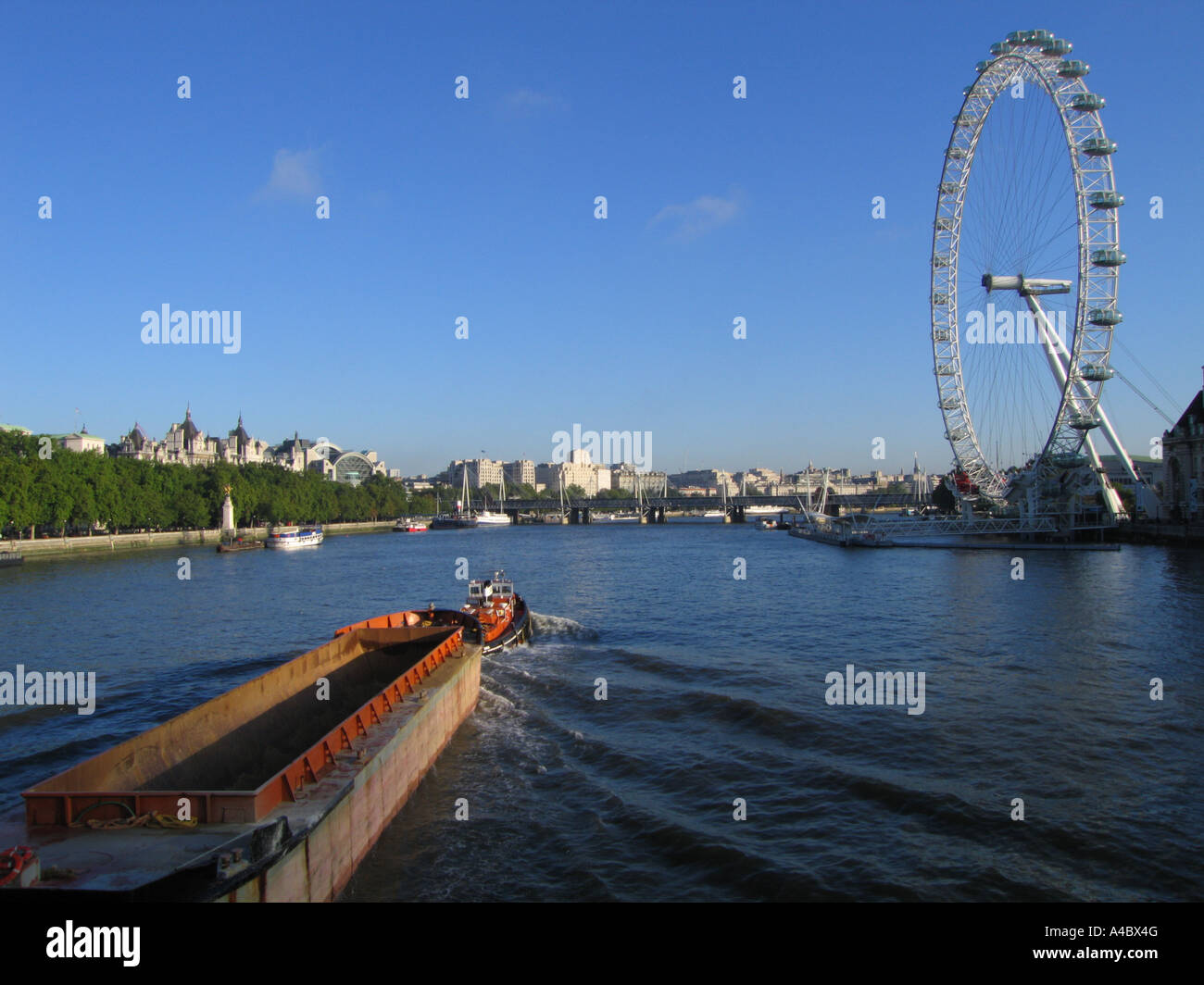 Barge being towed by tugboat past the London Eye Millenium Wheel River ...