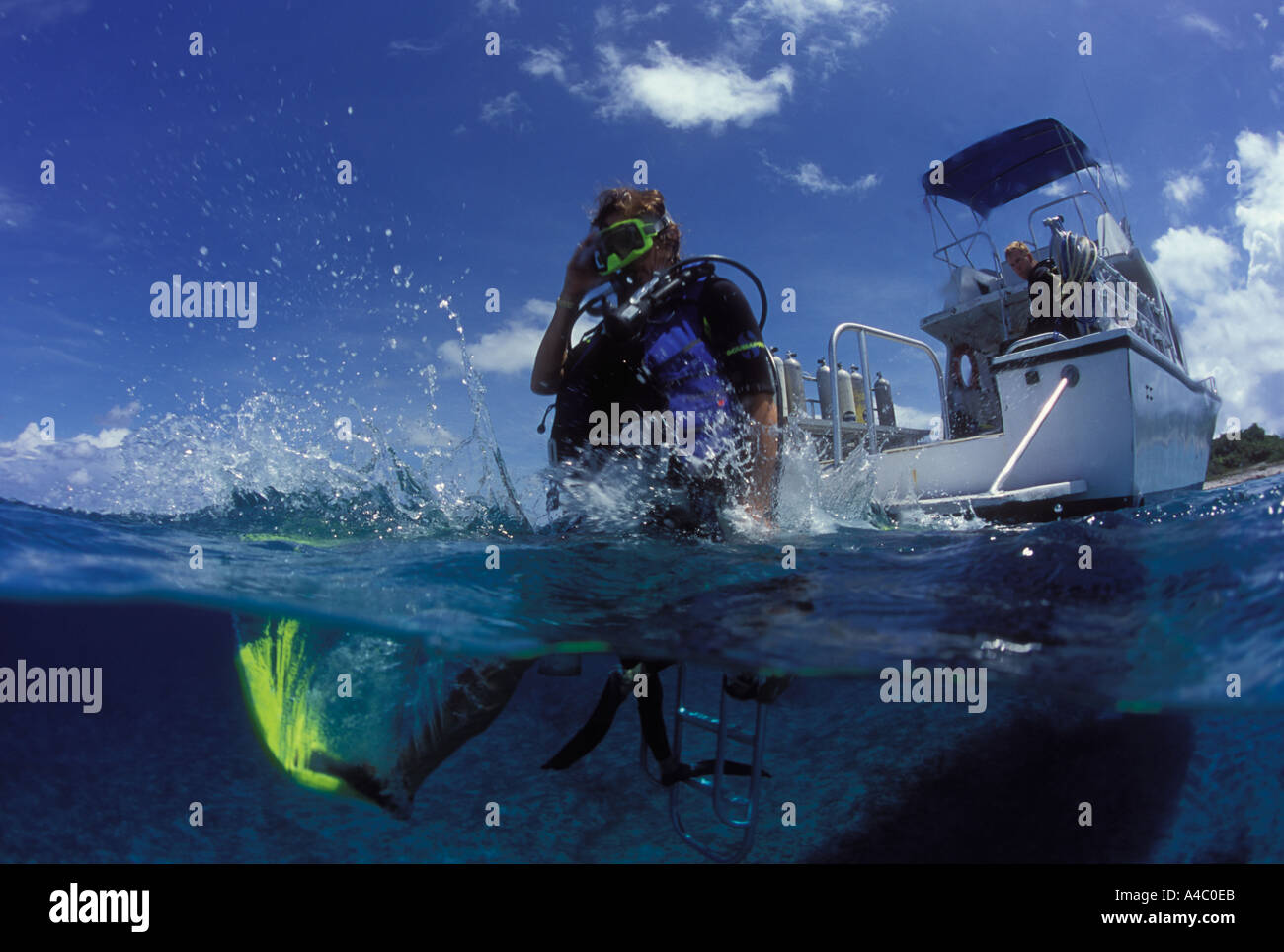 MALE DIVER DOES GIANT STRIDE ENTRY FROM BOAT INTO WATER IN THE CAYMAN ...