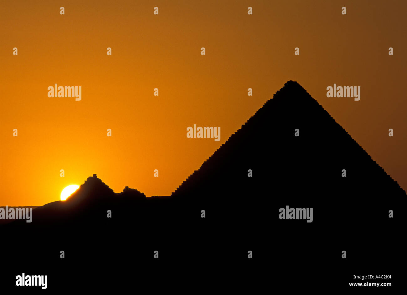 Sunset setting behind the silhouettes of the Great pyramids of Giza ...