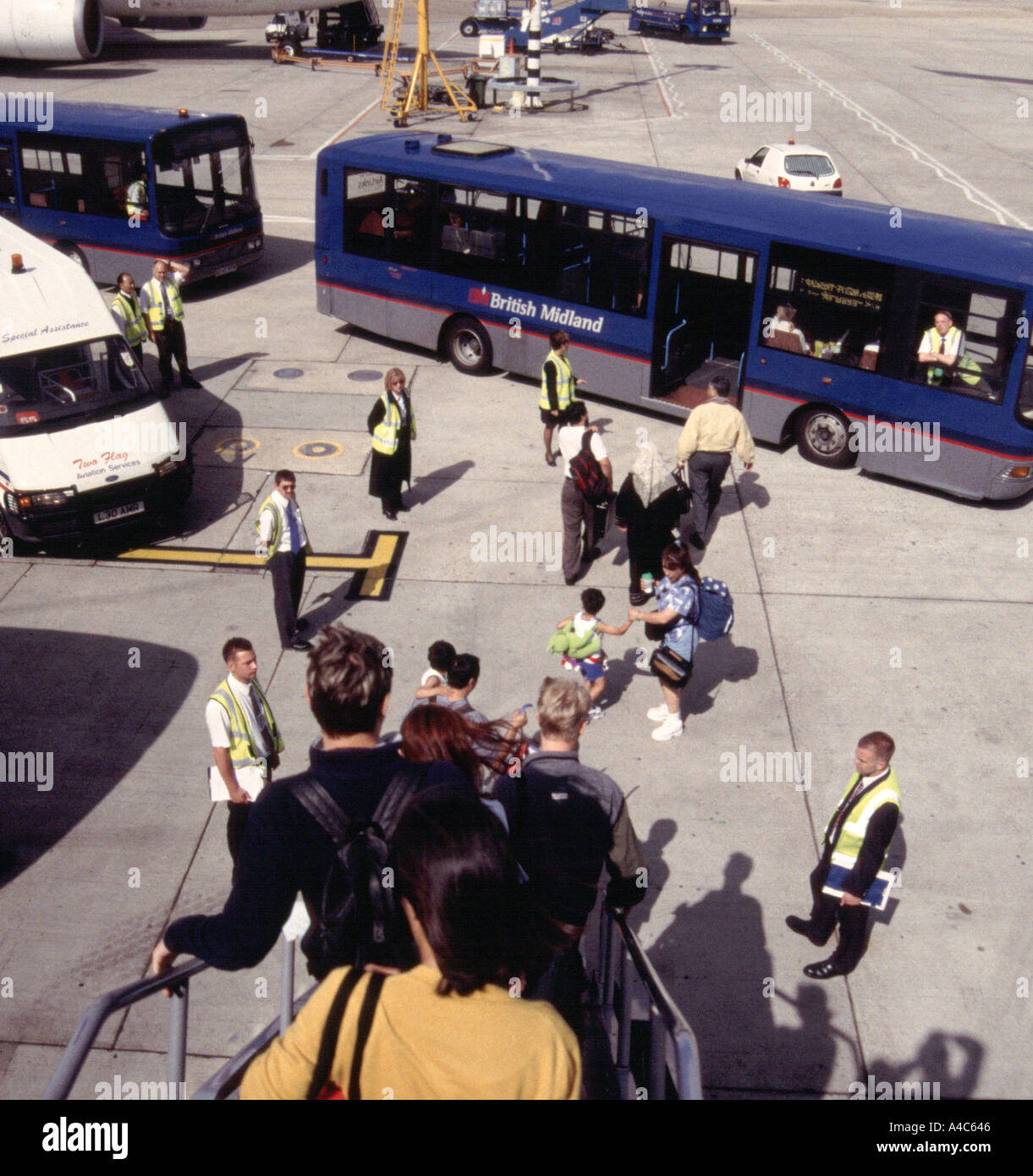 Passengers disembarking aircraft down steps and onto transfer bus Stock ...