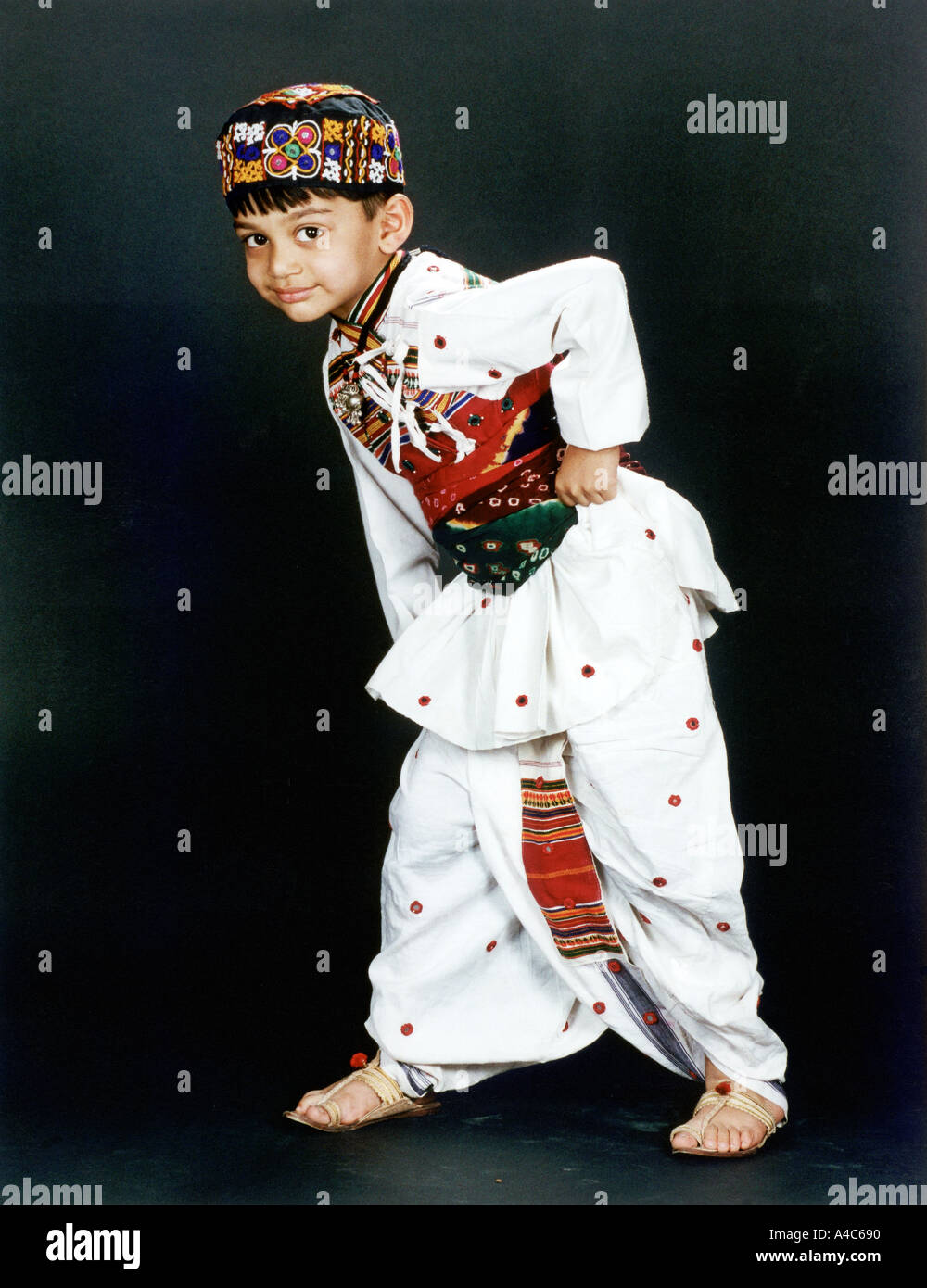 A boy dressed in traditional Indian attire, wearing an embroidered cap ...