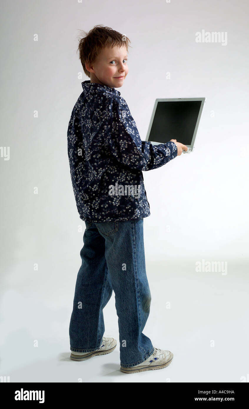 Boy, 8 years old, holding laptop in studio Stock Photo - Alamy