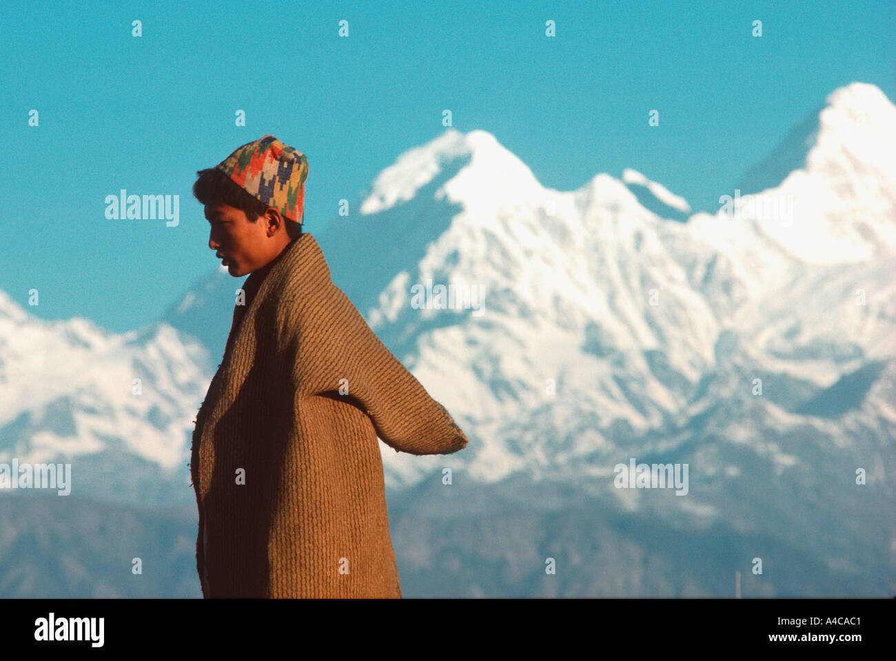 Gurung villager in woven rain cape seen against backdrop of Himalchuli ...