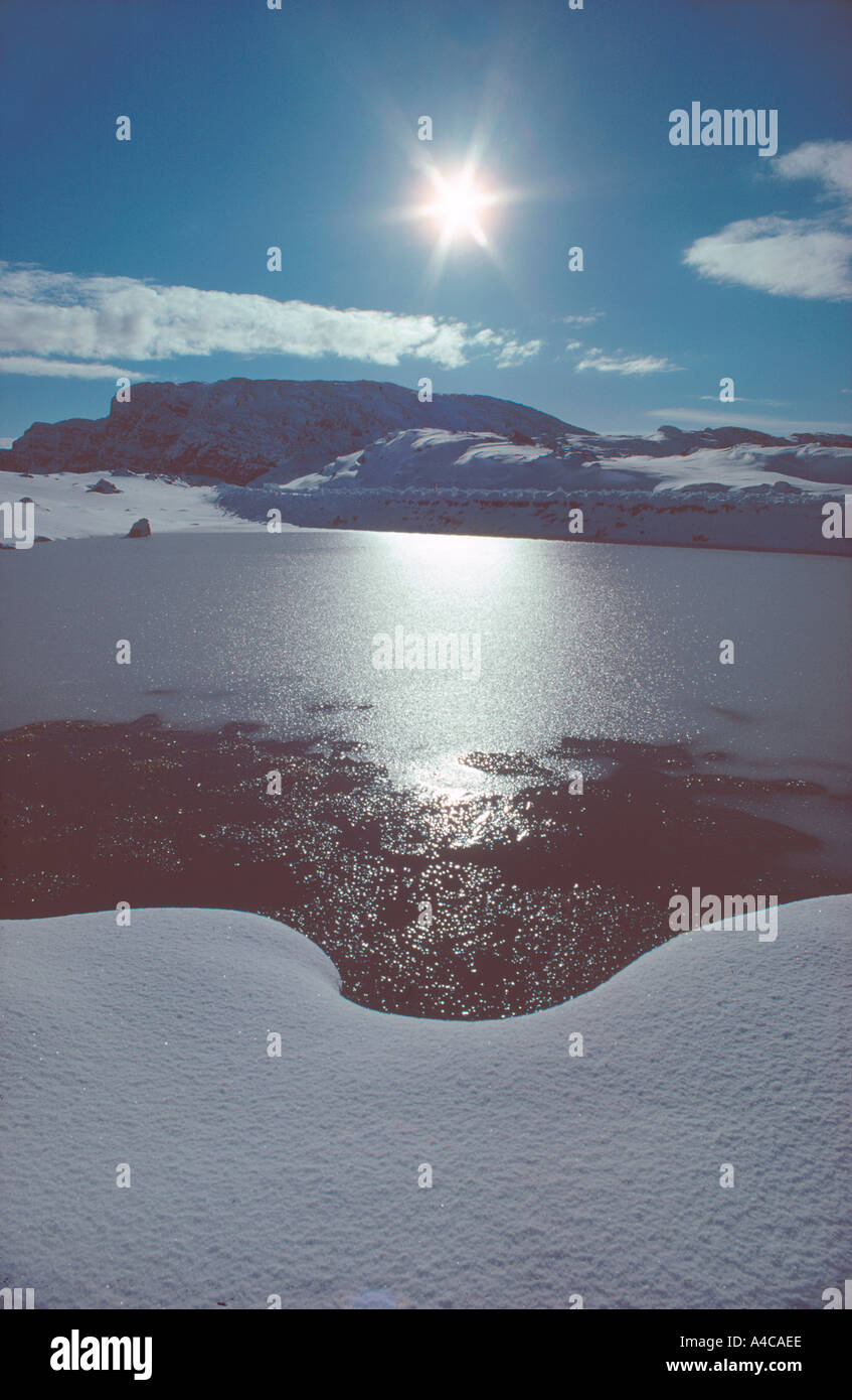 Low sun reflects in wintry pool surrounded by snow Applecross hills ...