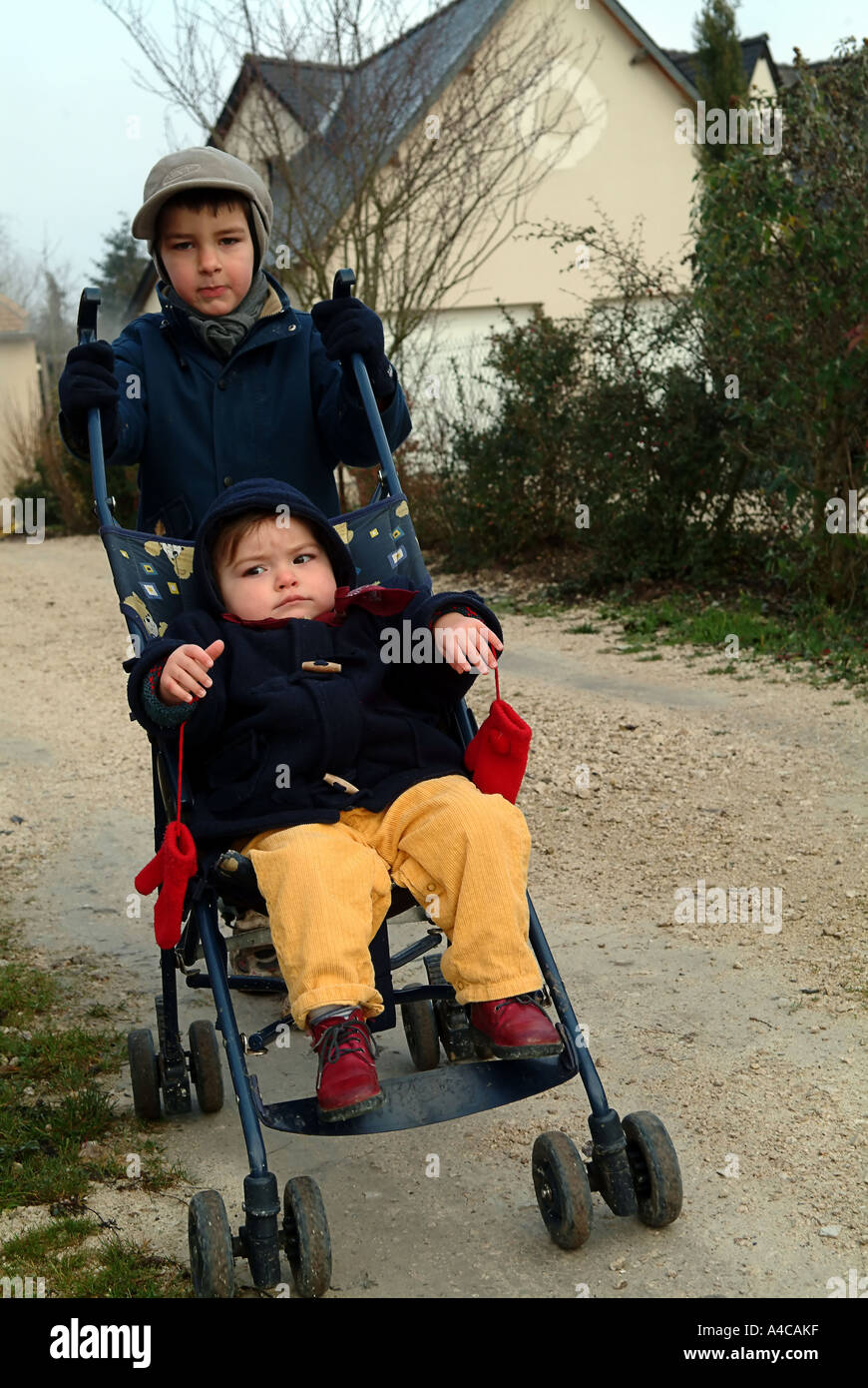 On the way to the playground - boy pushing his sister pushchair Stock ...