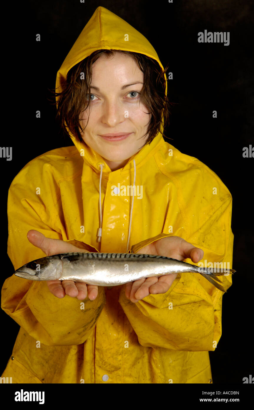 A woman in yellow oilskins holding raw fish Stock Photo - Alamy