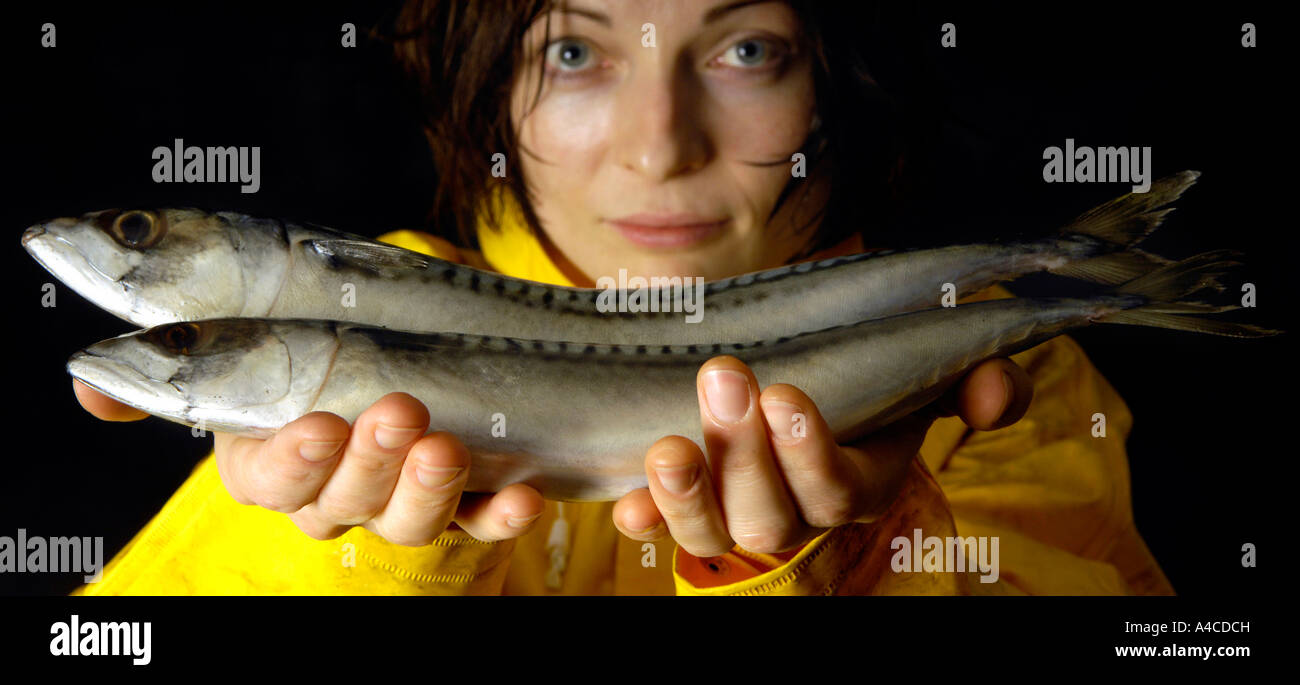 A woman in yellow oilskins holding raw fish Stock Photo - Alamy