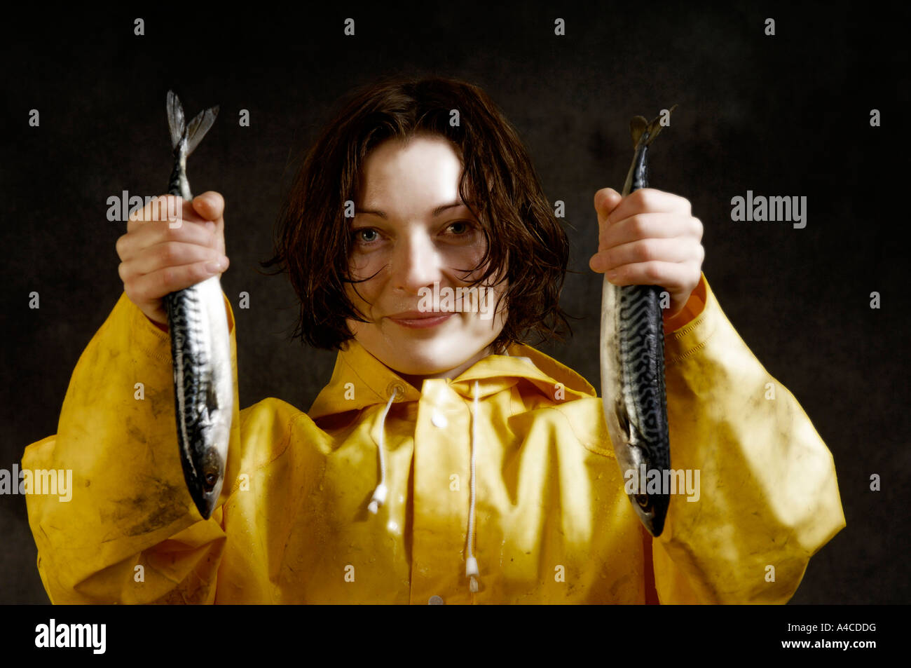 A woman in yellow oilskins holding raw fish Stock Photo - Alamy