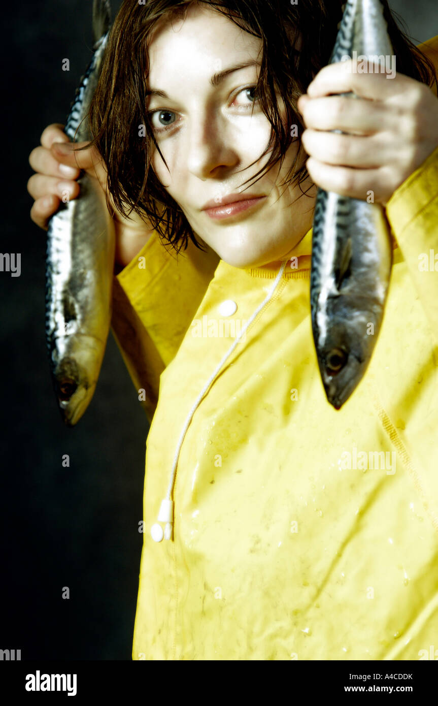 A woman in yellow oilskins holding raw fish Stock Photo - Alamy
