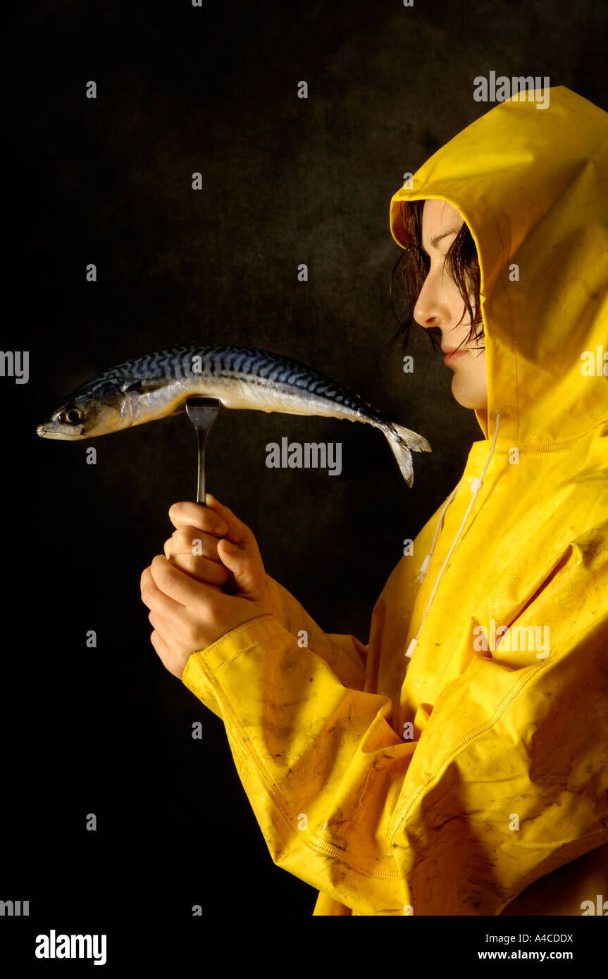 A woman in yellow oilskins holding raw fish Stock Photo - Alamy