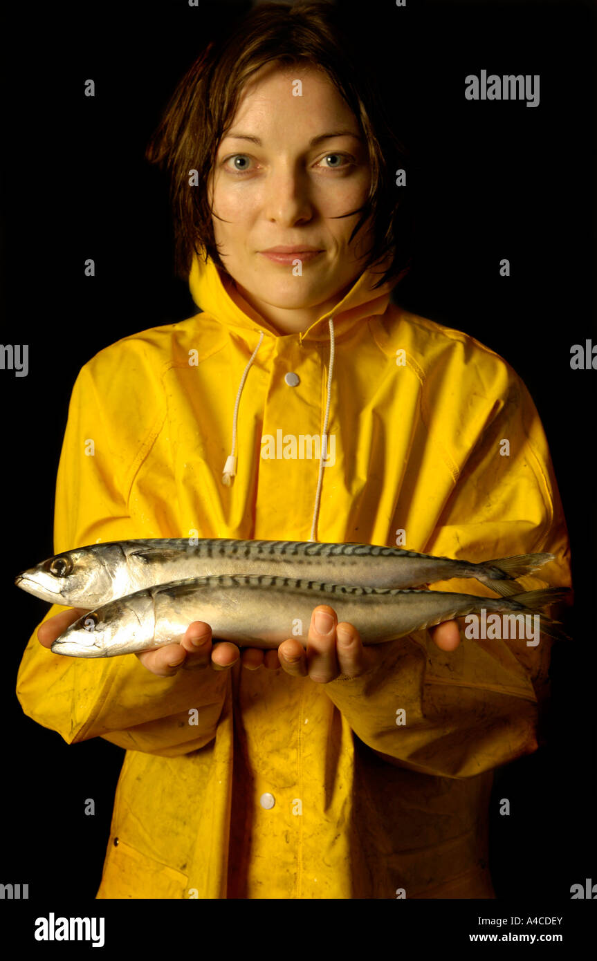 A woman in yellow oilskins holding raw fish Stock Photo - Alamy