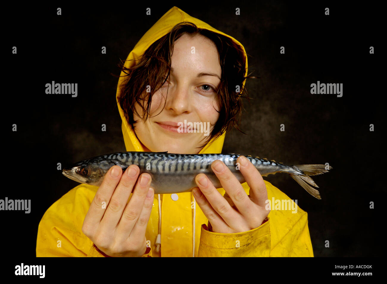 A woman in yellow oilskins holding raw fish Stock Photo - Alamy