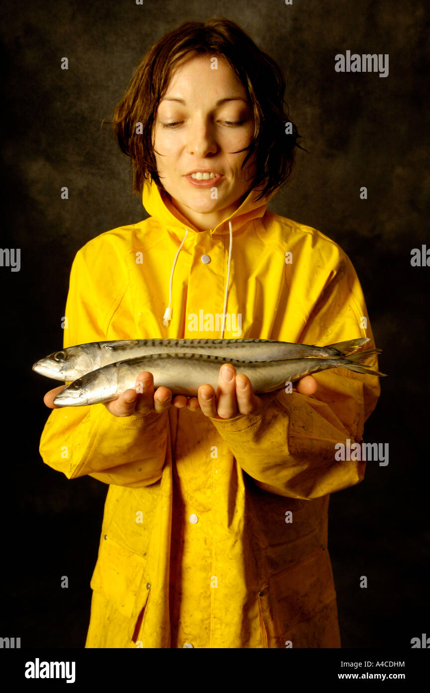 A woman in yellow oilskins holding raw fish Stock Photo - Alamy