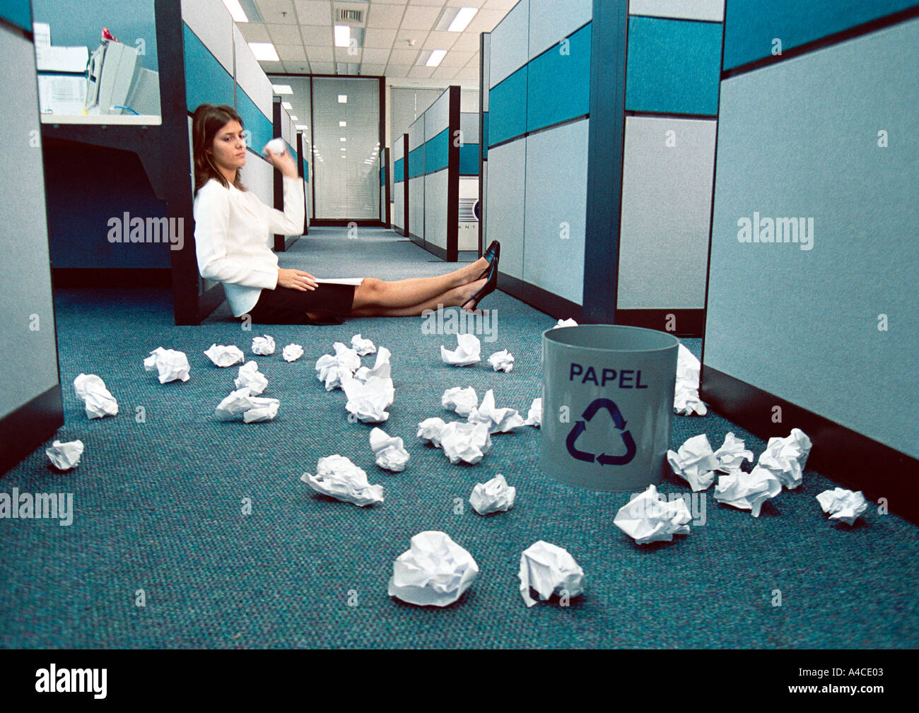 A woman office worker throws paper wads in a recycling basket in an ...